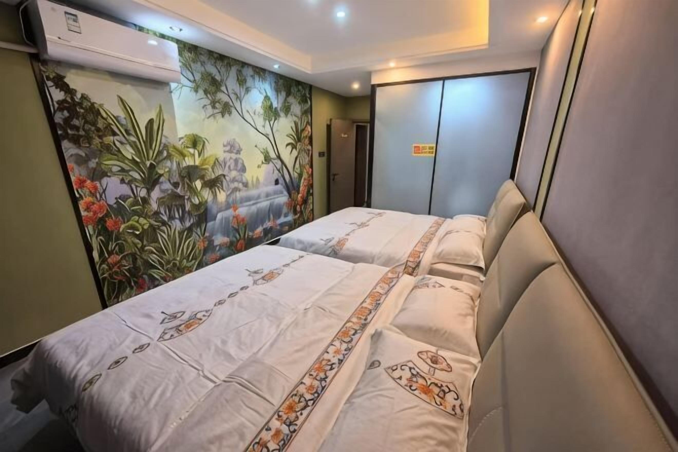 Quarto de hotel com duas camas, um mural na parede e um guarda-roupa.