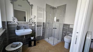 Casa de banho com lavatório branco, espelho, cabine de duche e sanita.