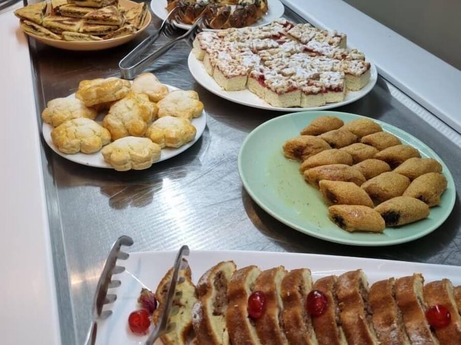 Um buffet com diversos pastéis e sobremesas, incluindo scones, muffins e um bolo com cobertura de cereja.