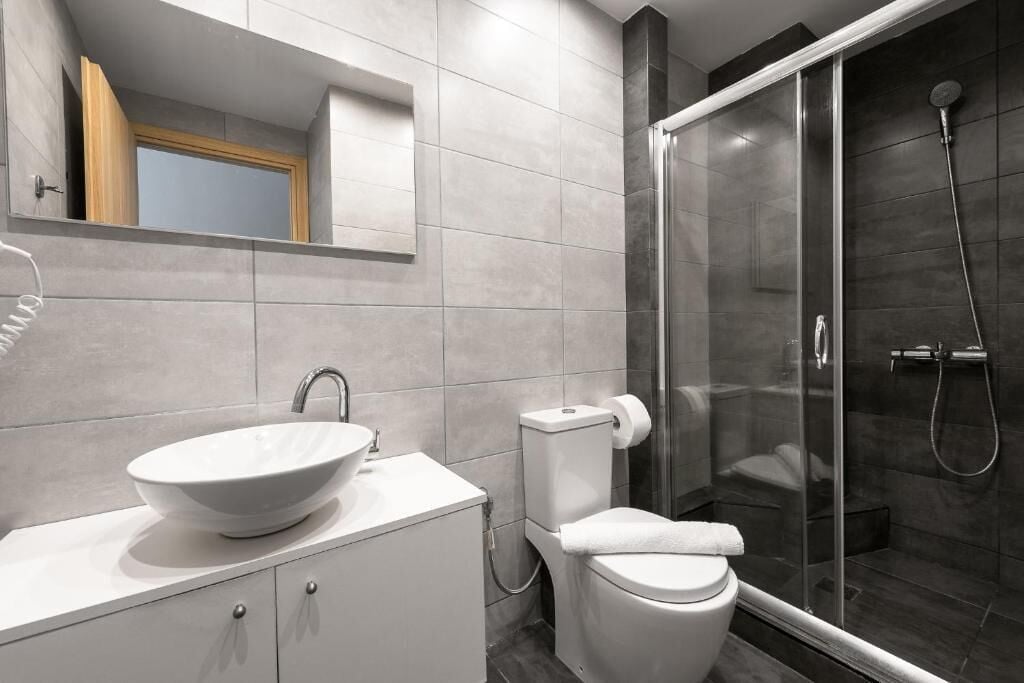 Uma casa de banho moderna com lavatório branco, sanita e cabine de duche em vidro.
