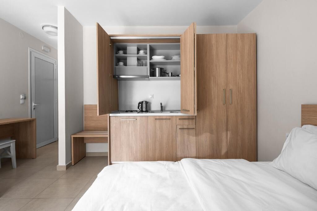Quarto de hotel pequeno com cozinha compacta, uma cama e um espaço de estar.
