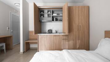 Quarto de hotel pequeno com cozinha compacta, uma cama e um espaço de estar.