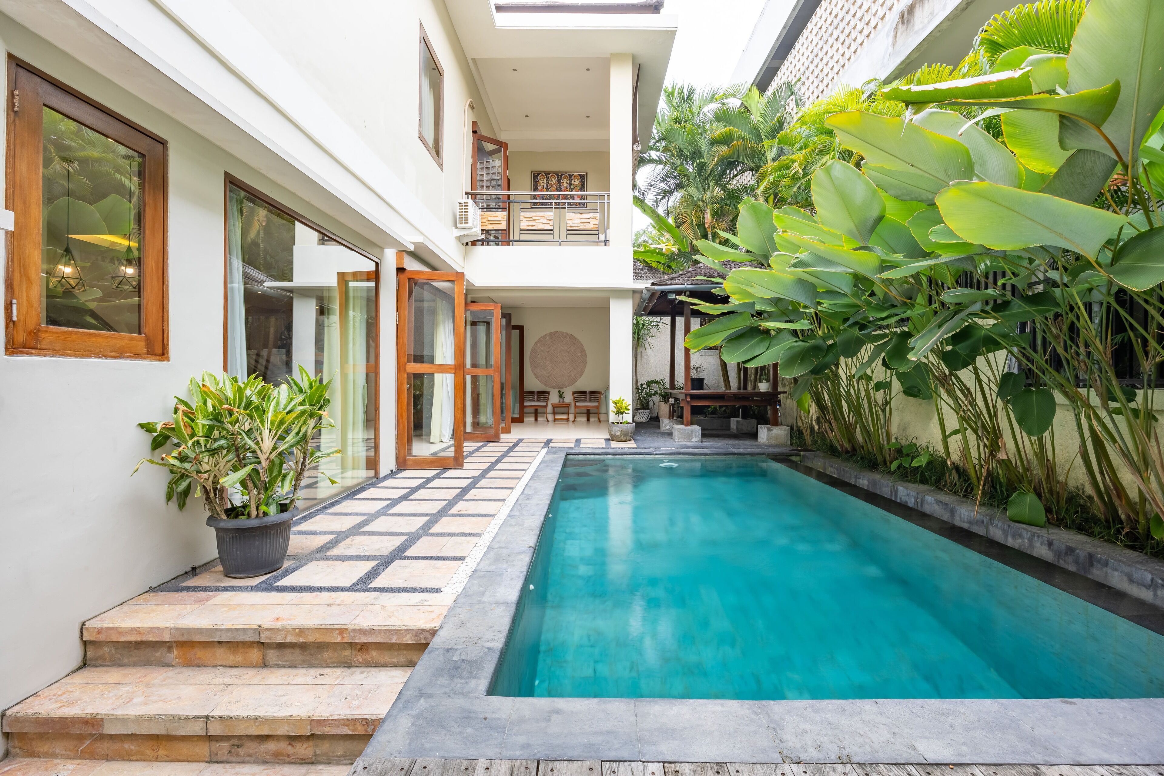 Uma casa moderna com piscina, varanda e vegetação exuberante.