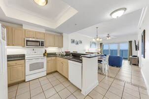 Condo com design assinado, 2 quartos, sacada, ao lado da praia | Cozinha privada | Geladeira, micro-ondas, fogão, cooktop