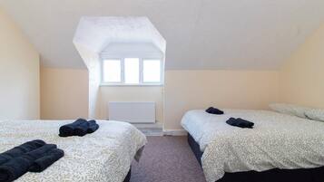 Quarto com duas camas, uma janela e um radiador.