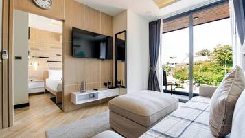 Quarto de hotel moderno com cama, televisão, sofá e varanda com vista.