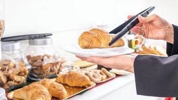 Disposição de buffet com croissants, bananas e outras iguarias.