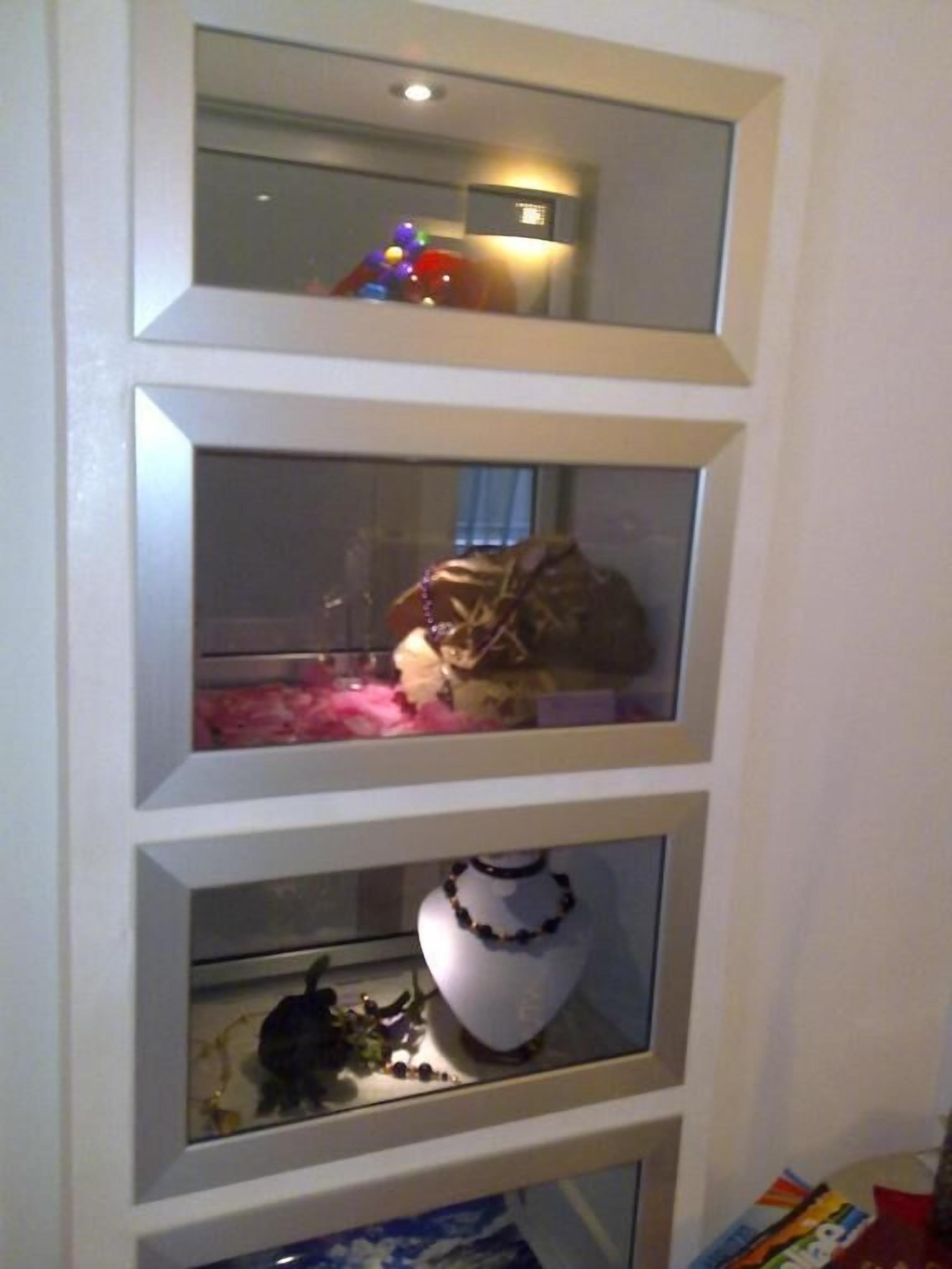 Vitrine em vários níveis com diversos itens, incluindo um manequim e objetos decorativos.