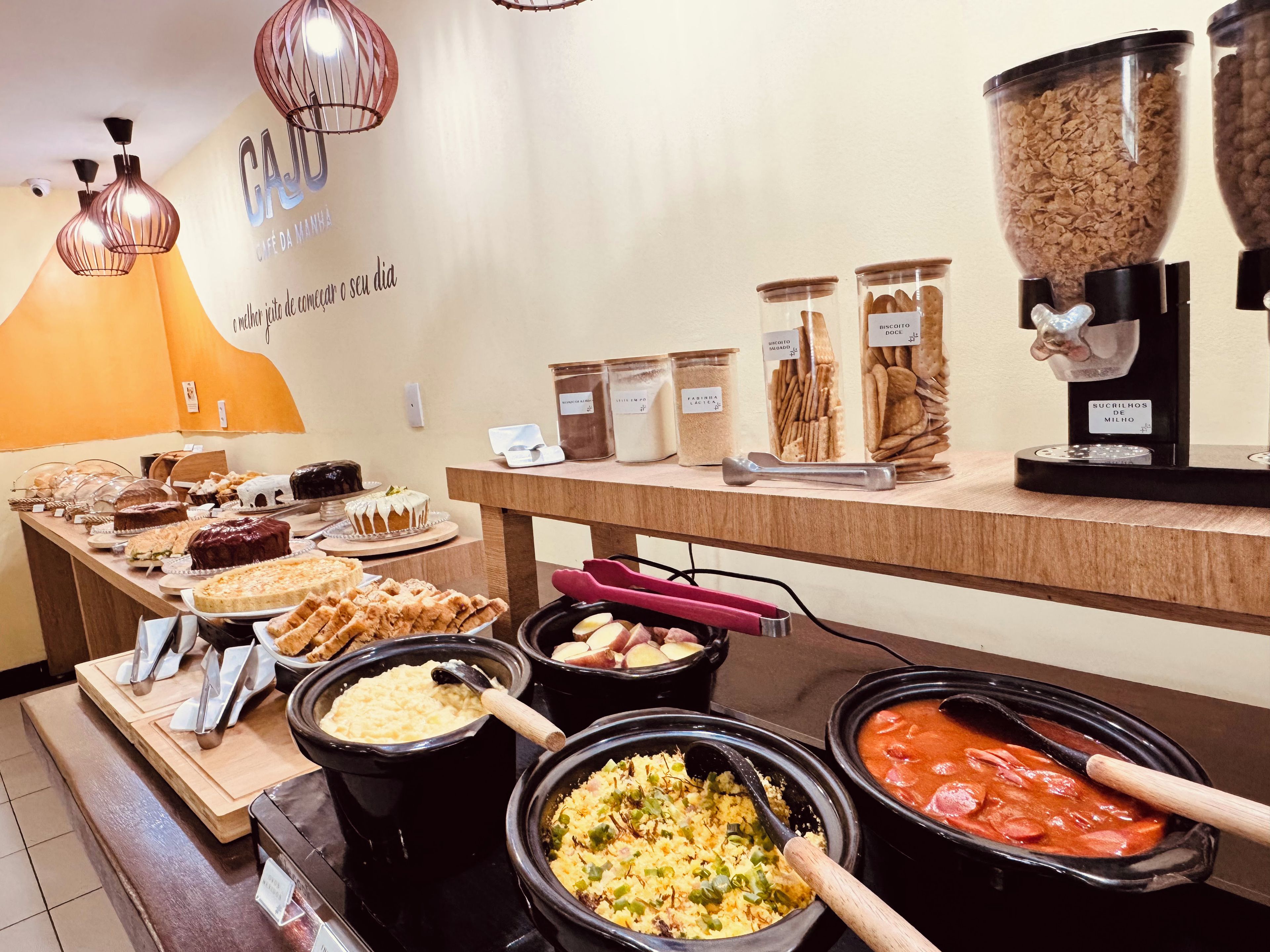 Buffet com diversos pratos, incluindo bolos, doces e opções quentes.