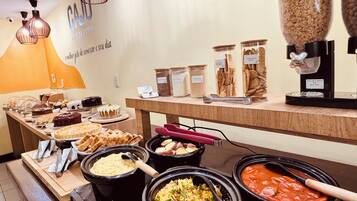 Buffet com diversos pratos, incluindo bolos, doces e opções quentes.
