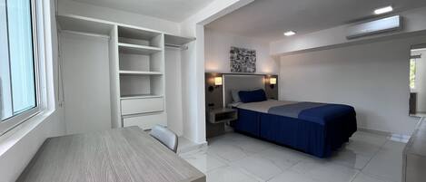 Quarto moderno com cama, mesas de cabeceira, escrivaninha e guarda-roupa.