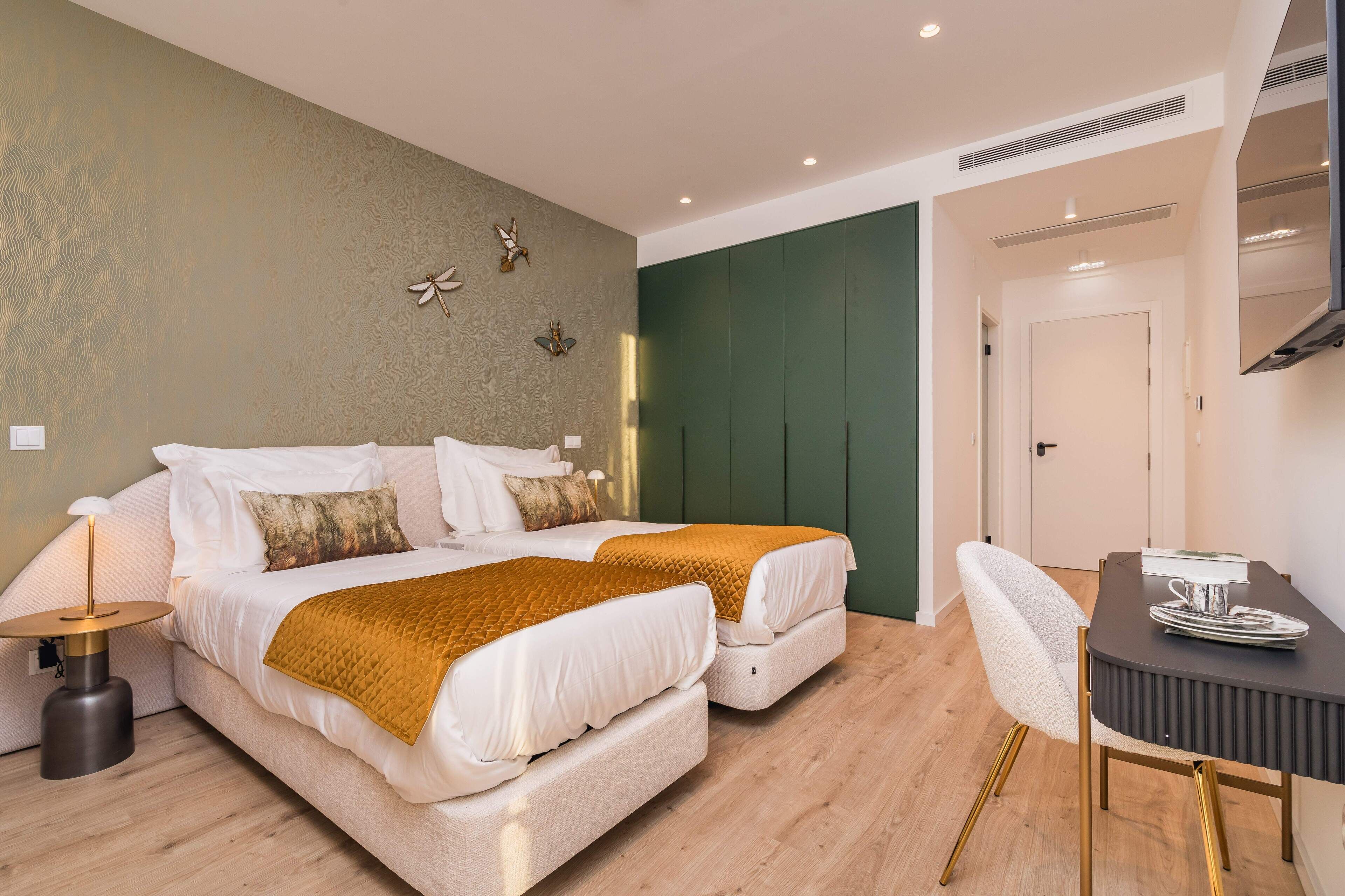 Quarto moderno com duas camas, uma escrivaninha e uma cadeira.