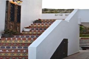 Escada com azulejos estampados levando a uma porta, com um candeeiro em cima.