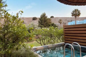 Piscina com deck de madeira e escada de metal, cercada por vegetação e uma paisagem montanhosa.