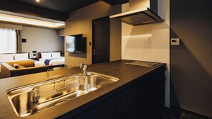 Quarto de hotel moderno com cozinha, cama e televisão.