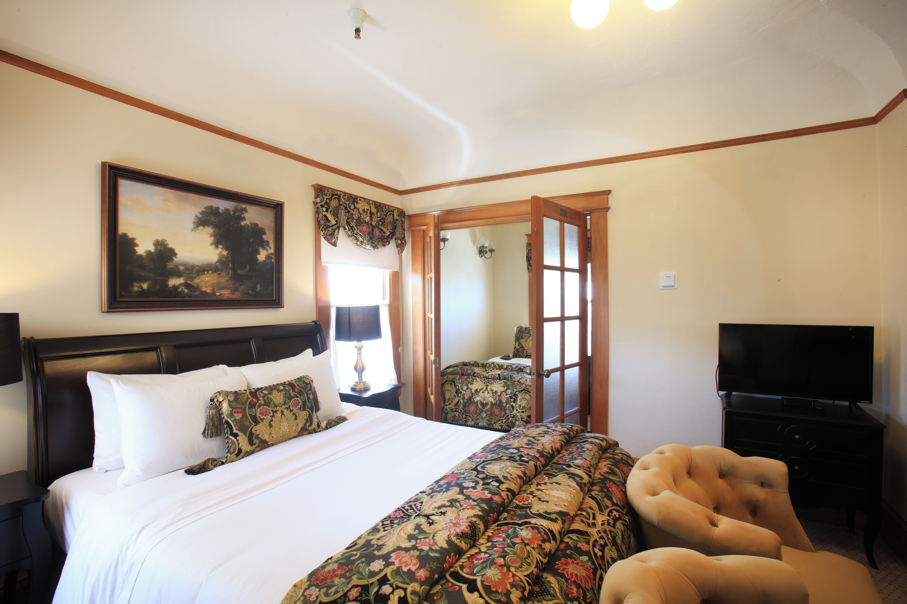 Quarto de hotel com uma cama grande, uma televisão e um espelho.