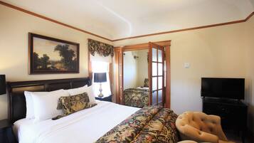 Quarto de hotel com uma cama grande, uma televisão e um espelho.