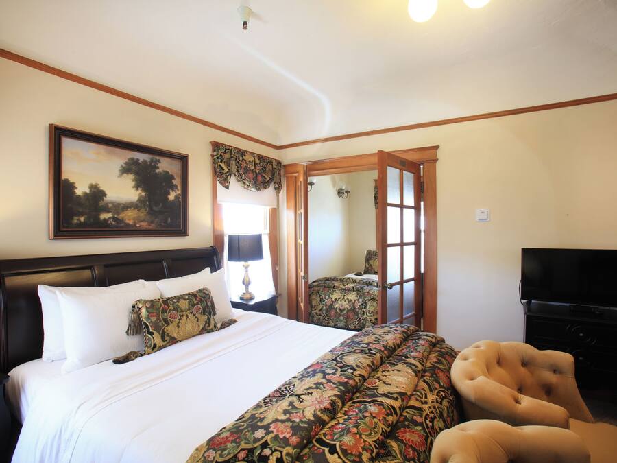 Quarto de hotel com uma cama grande, uma televisão e um espelho.