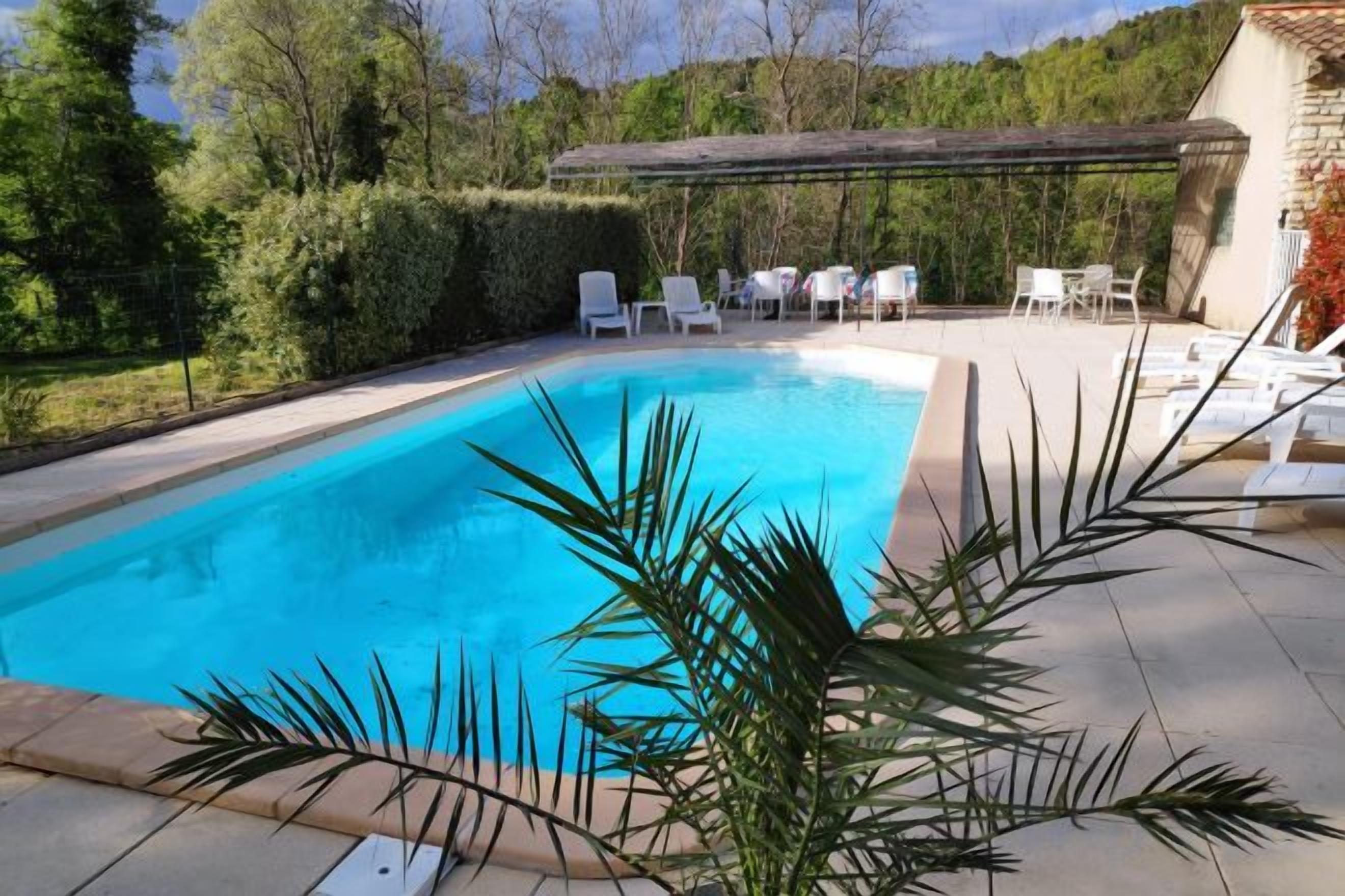 Piscina com espreguiçadeiras e área de estar coberta.