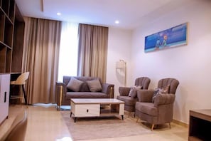 Uma sala de estar moderna com um sofá, duas poltronas, uma mesa de centro e um quadro na parede.