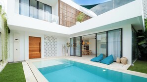 Uma casa moderna com piscina, porta de madeira e área de jantar com mesa e cadeiras.