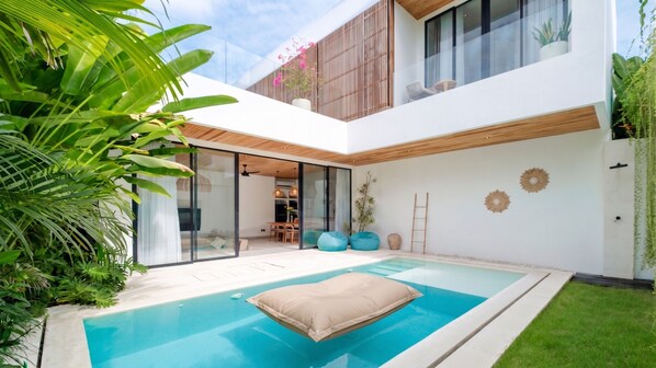 Uma casa moderna com piscina, portas de vidro e uma varanda com plantas.