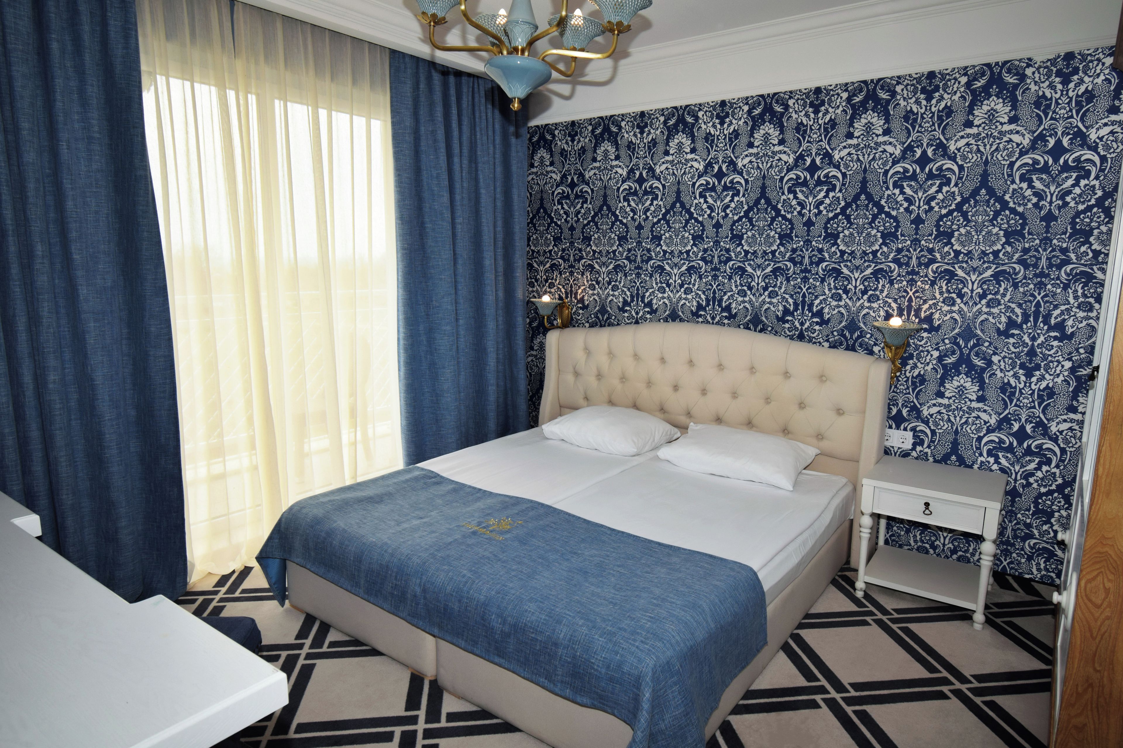 Quarto de hotel com uma cama grande, uma mesa de cabeceira e um criado-mudo.