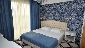 Quarto de hotel com uma cama grande, uma mesa de cabeceira e um criado-mudo.