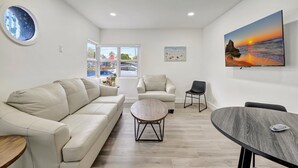 Uma sala de estar moderna com sofá, poltronas, uma mesa de centro redonda e uma mesa de jantar.