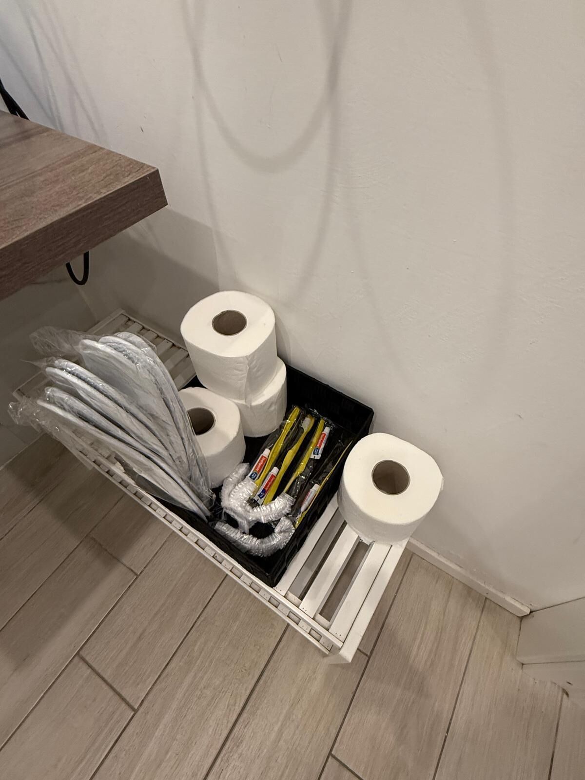 Armário com papel higiênico, produtos de limpeza e um saco plástico.