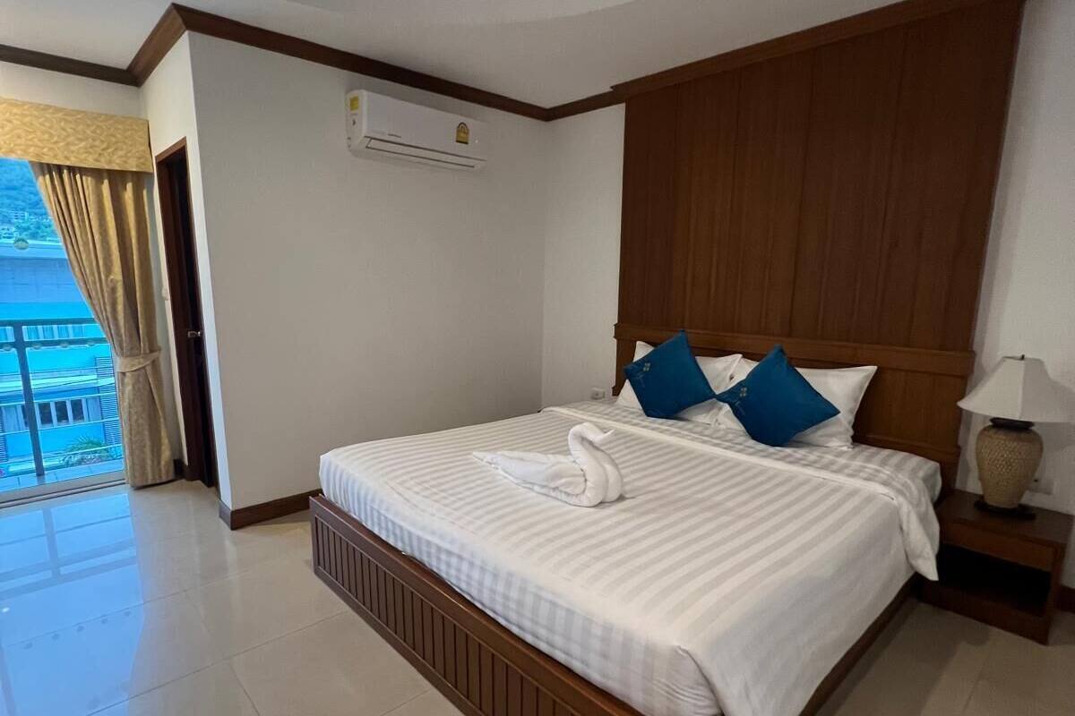 Quarto de hotel com uma cama grande, cabeceira de madeira e vista para o exterior.
