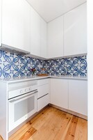 Cozinha com armários brancos, piso de madeira e backsplash com padrão azul.