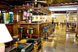 Uma área de bar com balcão, banquetes e um espaço de estar com sofá e cadeiras.