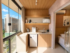 Quarto de hotel compacto com cozinha compacta, uma cama e vista para a paisagem urbana.