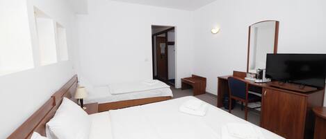 Quarto de hotel com uma cama grande, uma mesa de escritório com um computador, uma televisão e um pequeno espaço de estar.