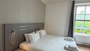 Quarto de hotel moderno com uma cama grande, mesas de cabeceira, uma janela com vista e aquecedor embutido.