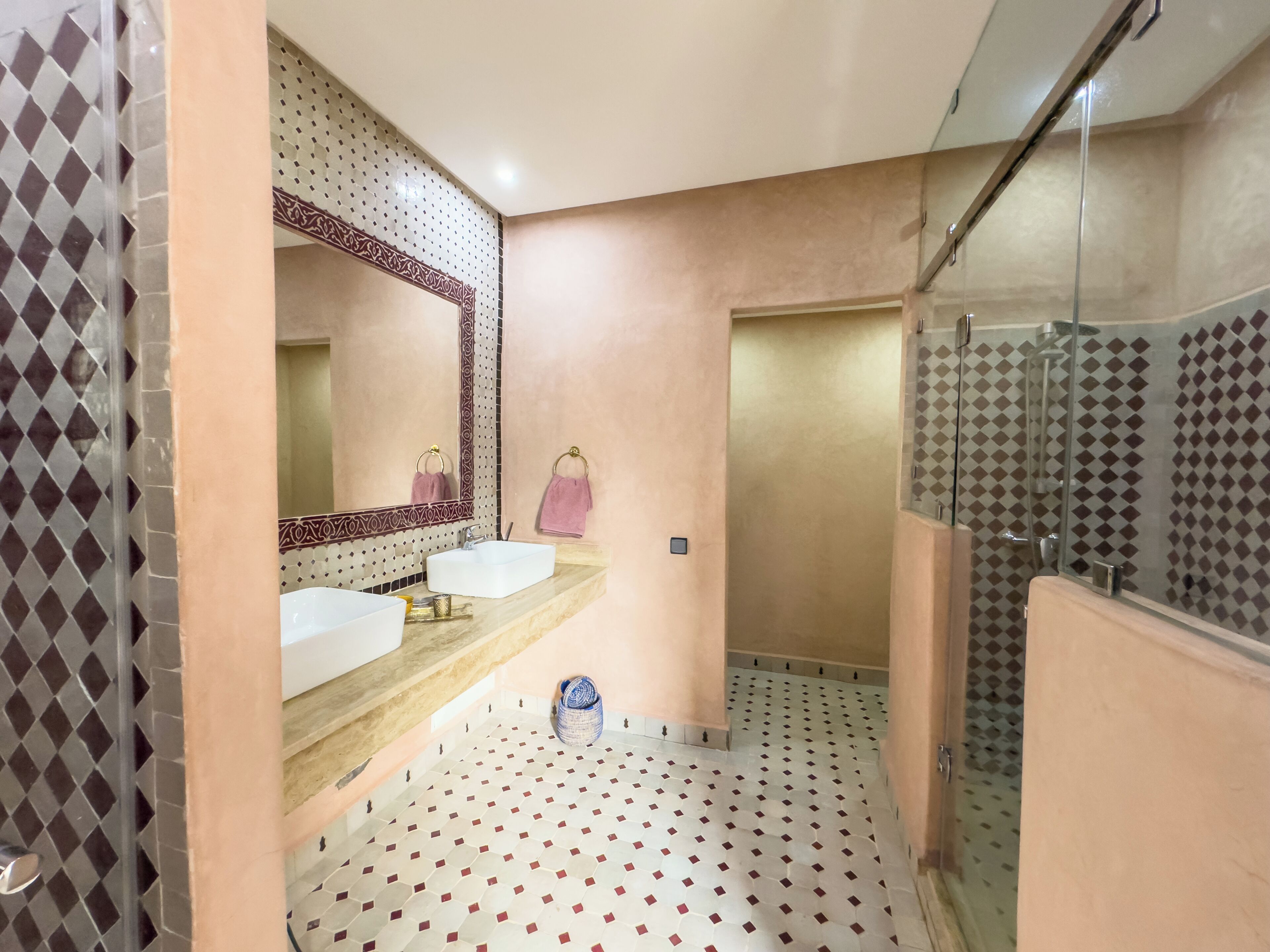Casa de banho com duas pias, um espelho e zona de duche.