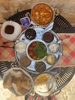 Uma refeição tradicional do Oriente Médio servida em uma bandeja de metal, com diversos pratos como ensopado, azeitonas, tomates e pão.
