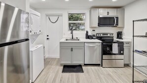 Cozinha compacta com eletrodomésticos de aço inoxidável, lava-louças e micro-ondas.