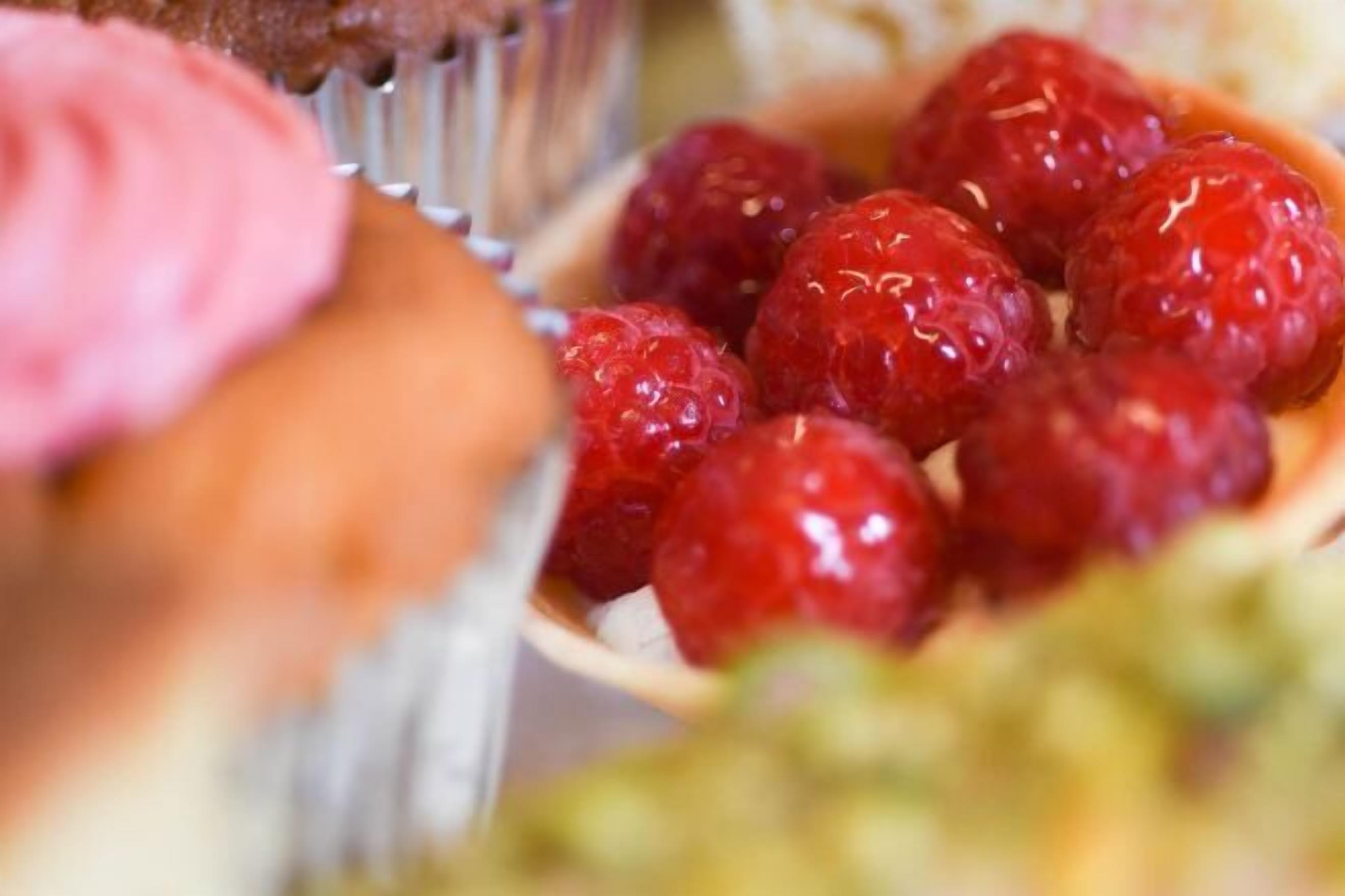 Close-up de uma bandeja com sobremesa, um pastel e framboesas.