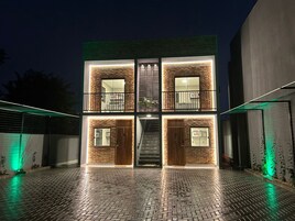 Um edifício moderno com fachada de tijolos, várias varandas e uma escadaria central.