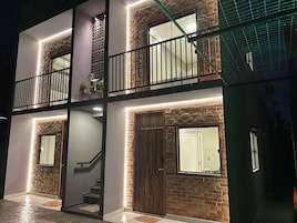 Um edifício moderno com fachada de tijolos, várias varandas e uma escadaria que leva a um andar superior.
