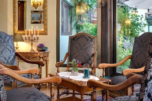 Quarto com mesa de madeira, duas cadeiras estofadas, espelho e vista para o verde lá fora.