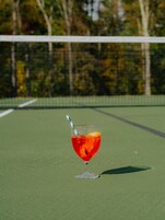 Uma quadra esportiva com um copo de bebida vermelha e uma fatia de laranja no chão.