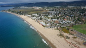 Vista aérea de uma vila costeira com praia, áreas residenciais e uma variedade de edifícios comerciais.