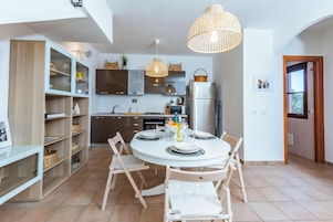 Uma cozinha moderna com uma mesa de jantar redonda, cadeiras de madeira e um lustre pendente.