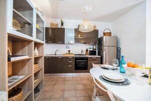 Uma cozinha moderna com prateleiras de madeira, uma mesa de jantar posta para dois e uma janela grande.