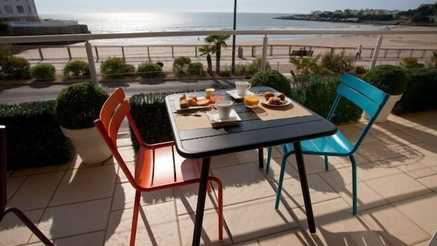 Mesa com alimentos de café da manhã e vista para a praia.
