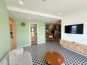 Uma sala de estar com sofá, mesa de centro, TV fixada na parede e piso estampado.