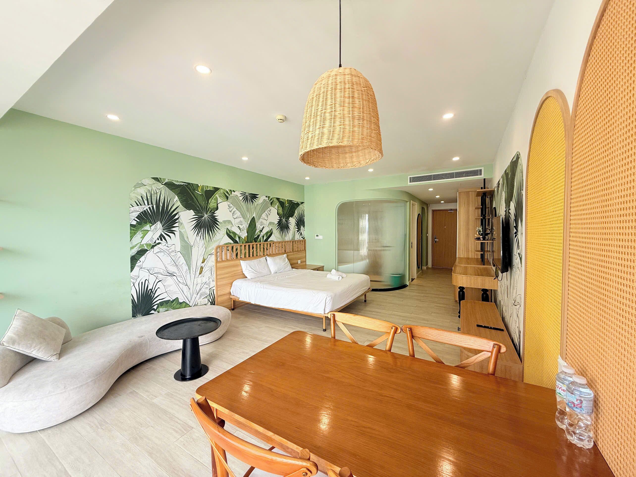 Quarto de hotel moderno com cama, mesa de jantar e um espelho grande.
